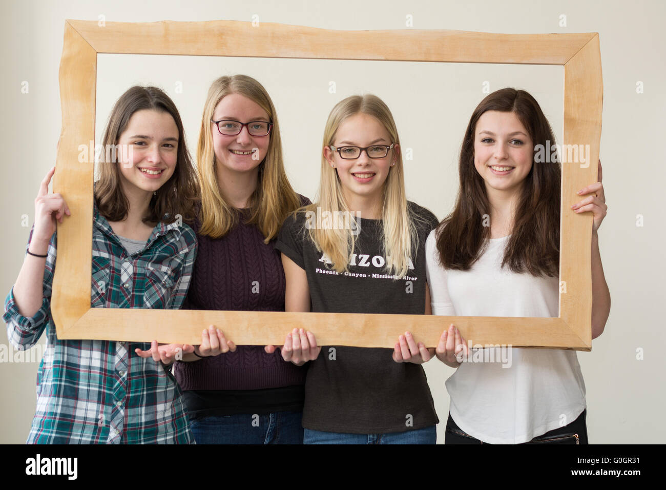 Girl group smiling through picture frame - Portrait Stock Photo - Alamy