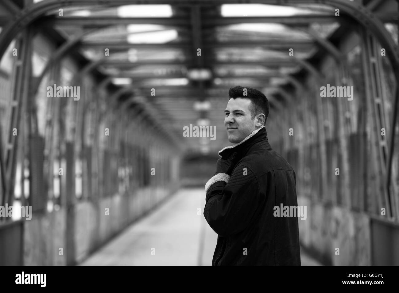 Attractive young man wearing leather jacket looking back over his ...