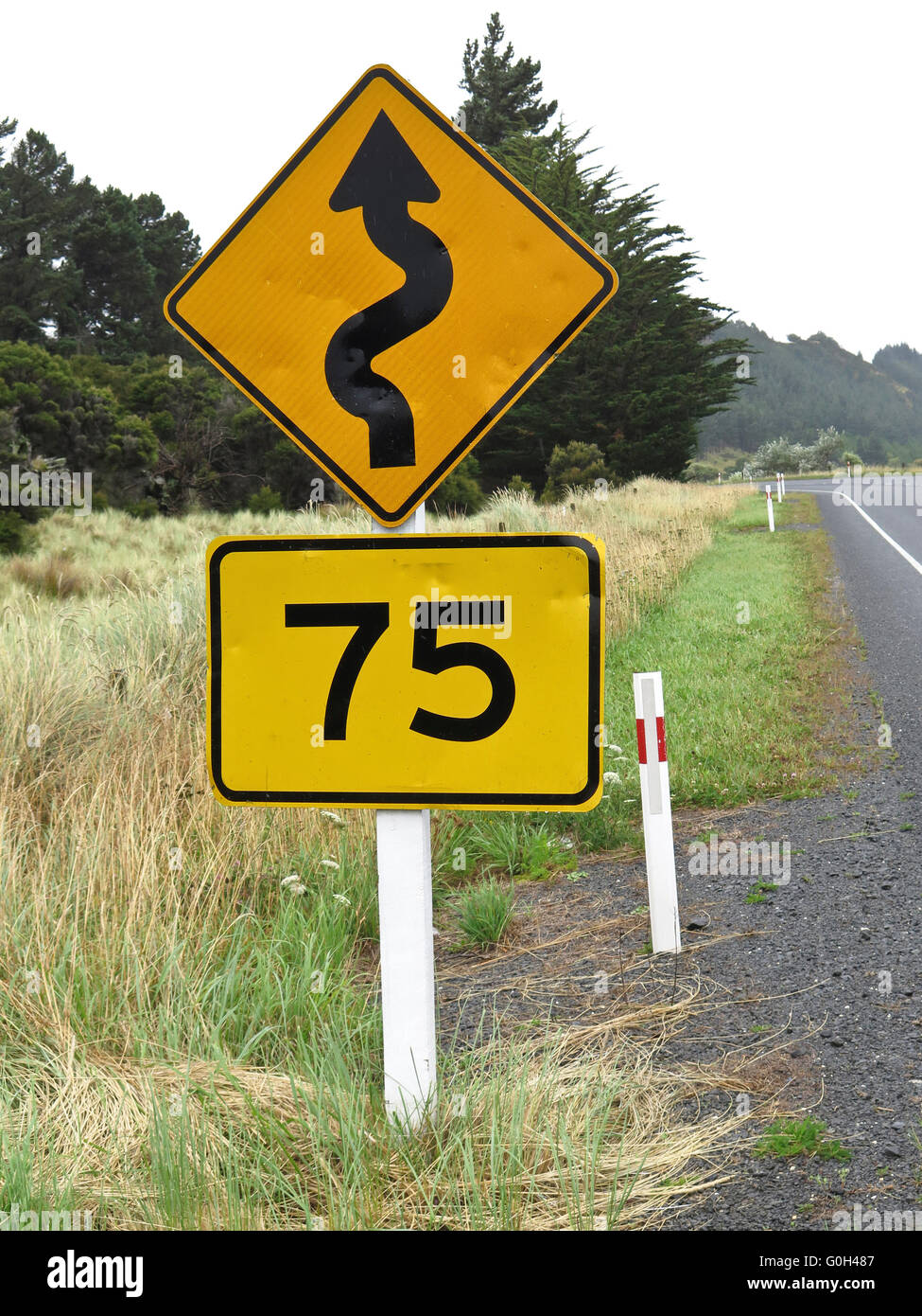 Bends in road sign in New Zealand. Maximum speed 75 kph Stock Photo - Alamy