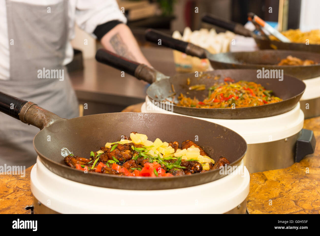 Row of woks with freshly cooked food on portable heating devices while ...