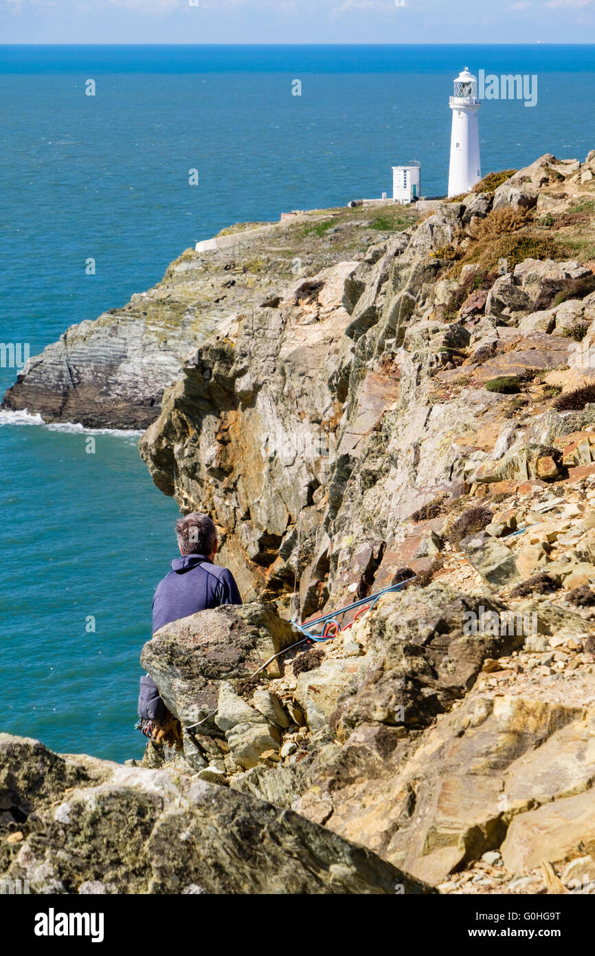 Gogarth coastal cliffs with rock climber above sea and lighthouse ...