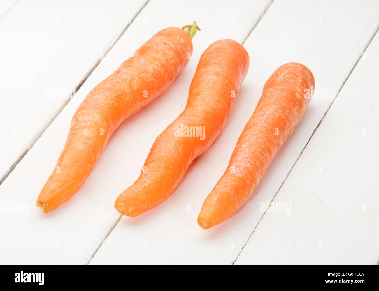 three fresh carrots washed on a white wooden table Stock Photo - Alamy