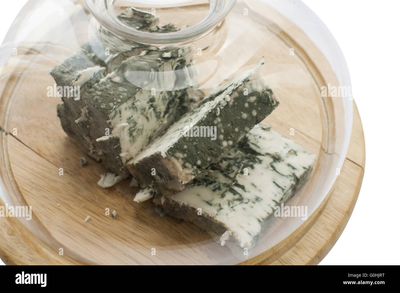 Sliced lump of moldy white cheese under glass lid on wooden tray ...