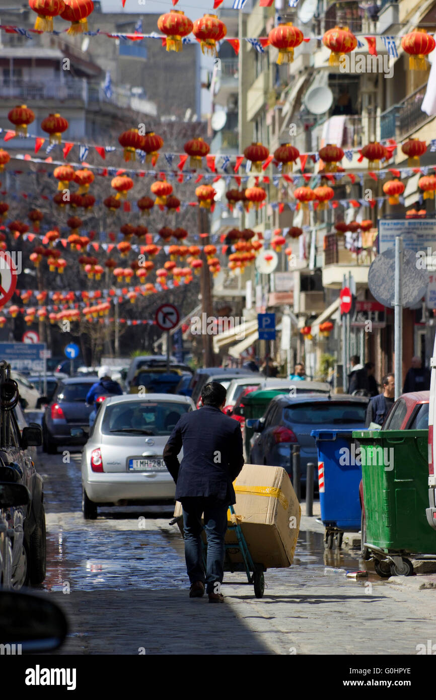 Chinese merchant pushing a hand truck (wheelbarrow) loaded with a large ...