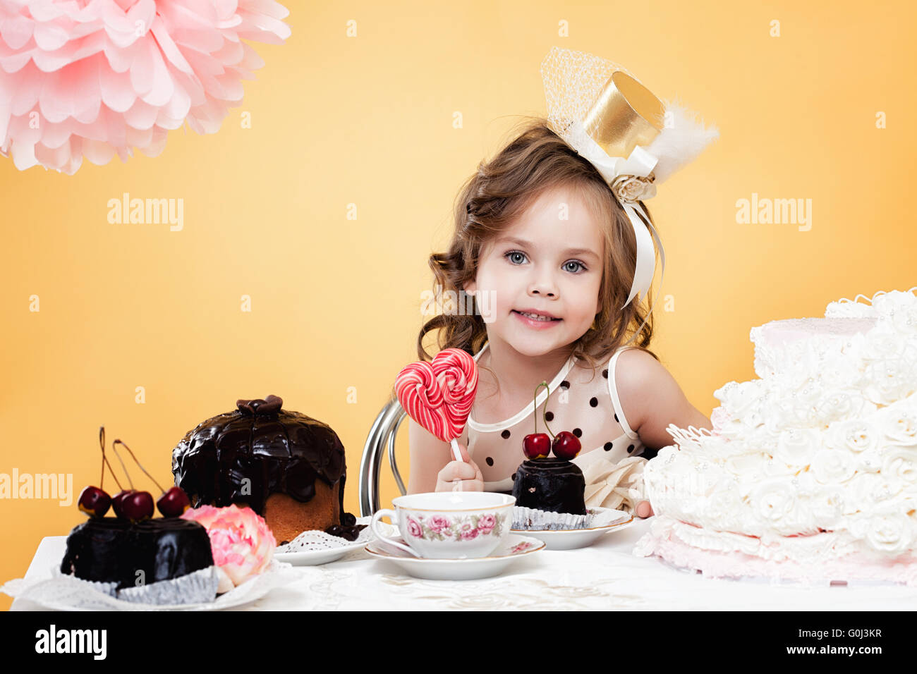 Cute girl posing with sweets, on yellow background Stock Photo - Alamy