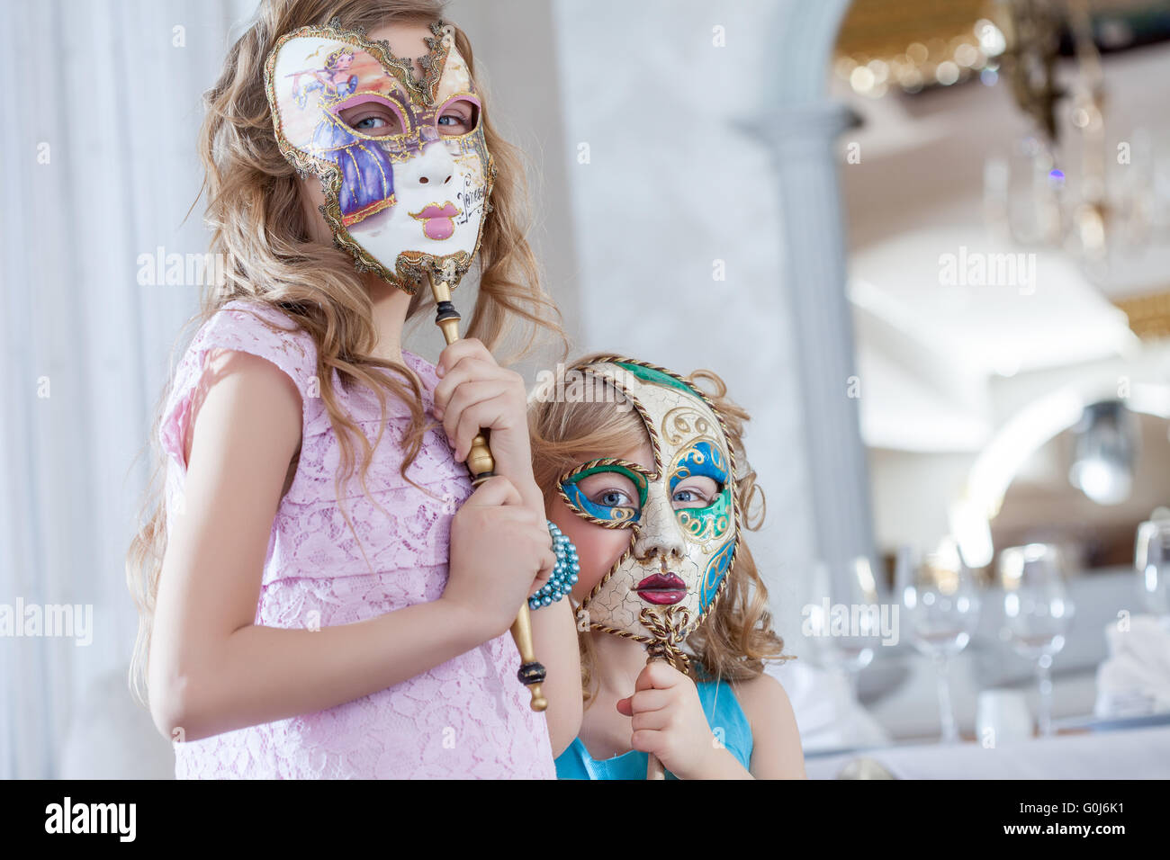 Cute sisters posing hiding faces behind masks Stock Photo - Alamy