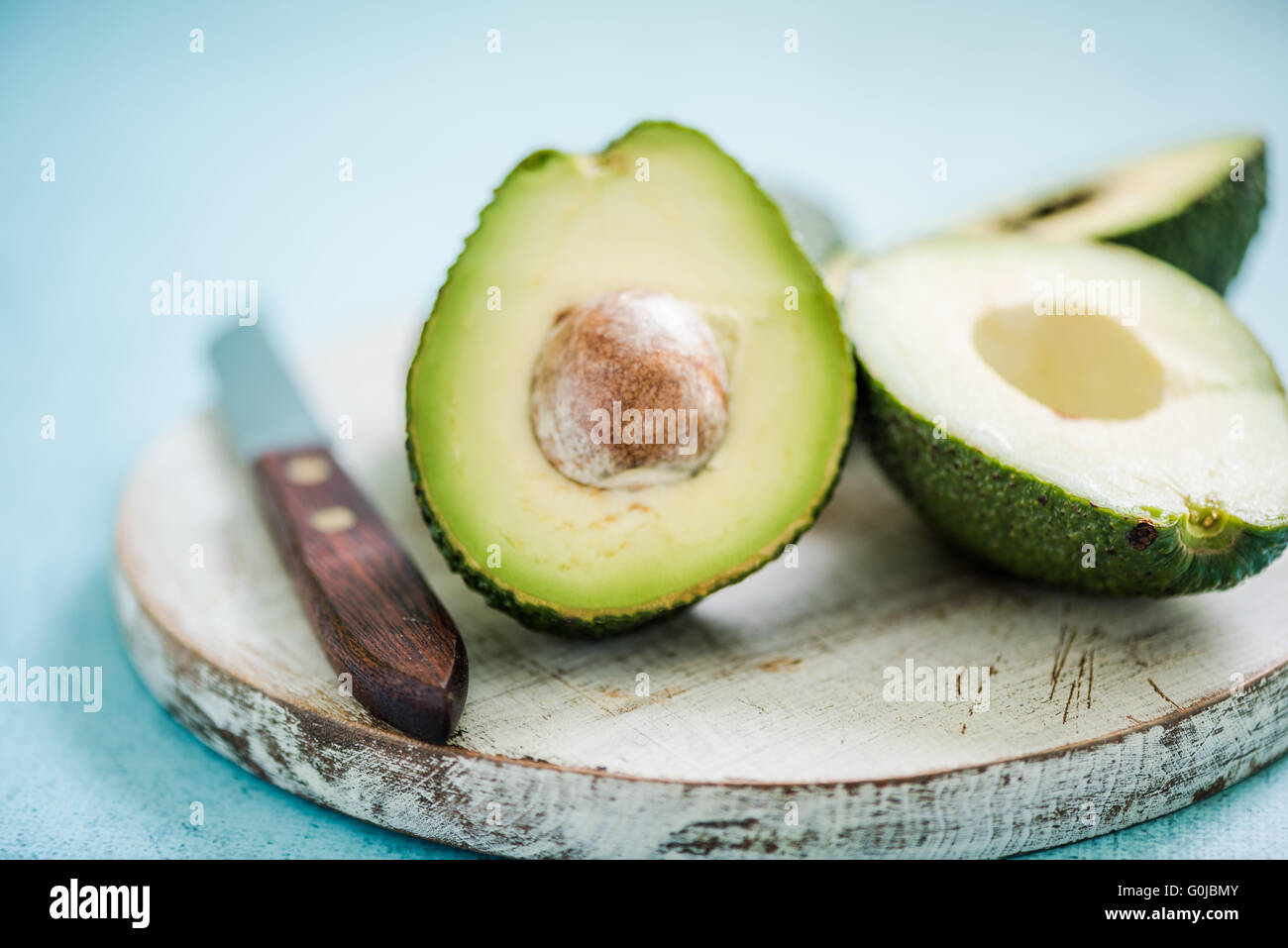 Whole and halved avocado with seed, vibrant pastel colors Stock Photo ...