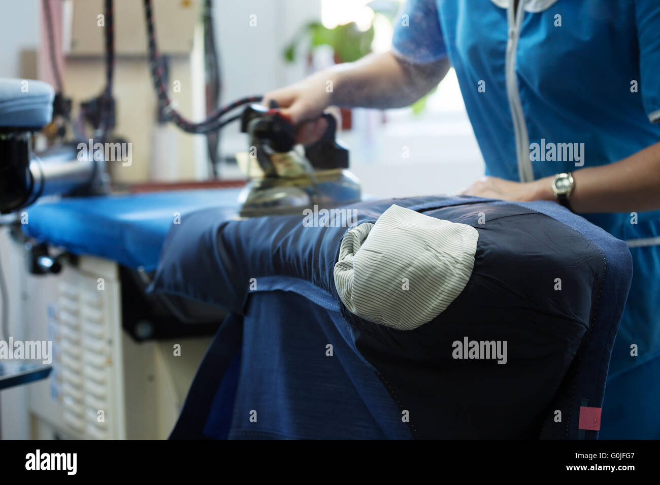 Work in laundry room - woman ironing new jacket Stock Photo - Alamy