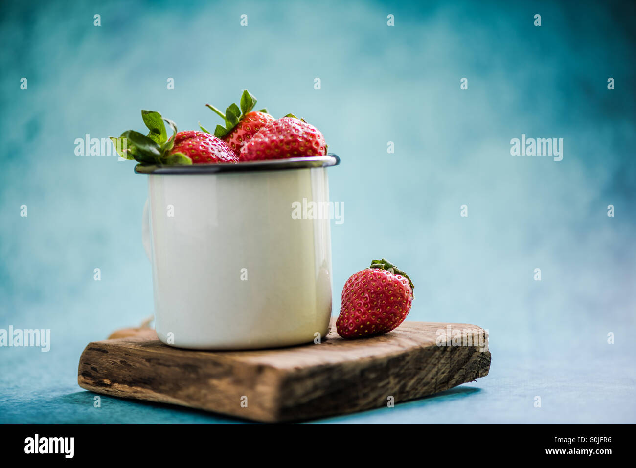 vintage jat with fresh strawberries, on blue vibrant background Stock ...