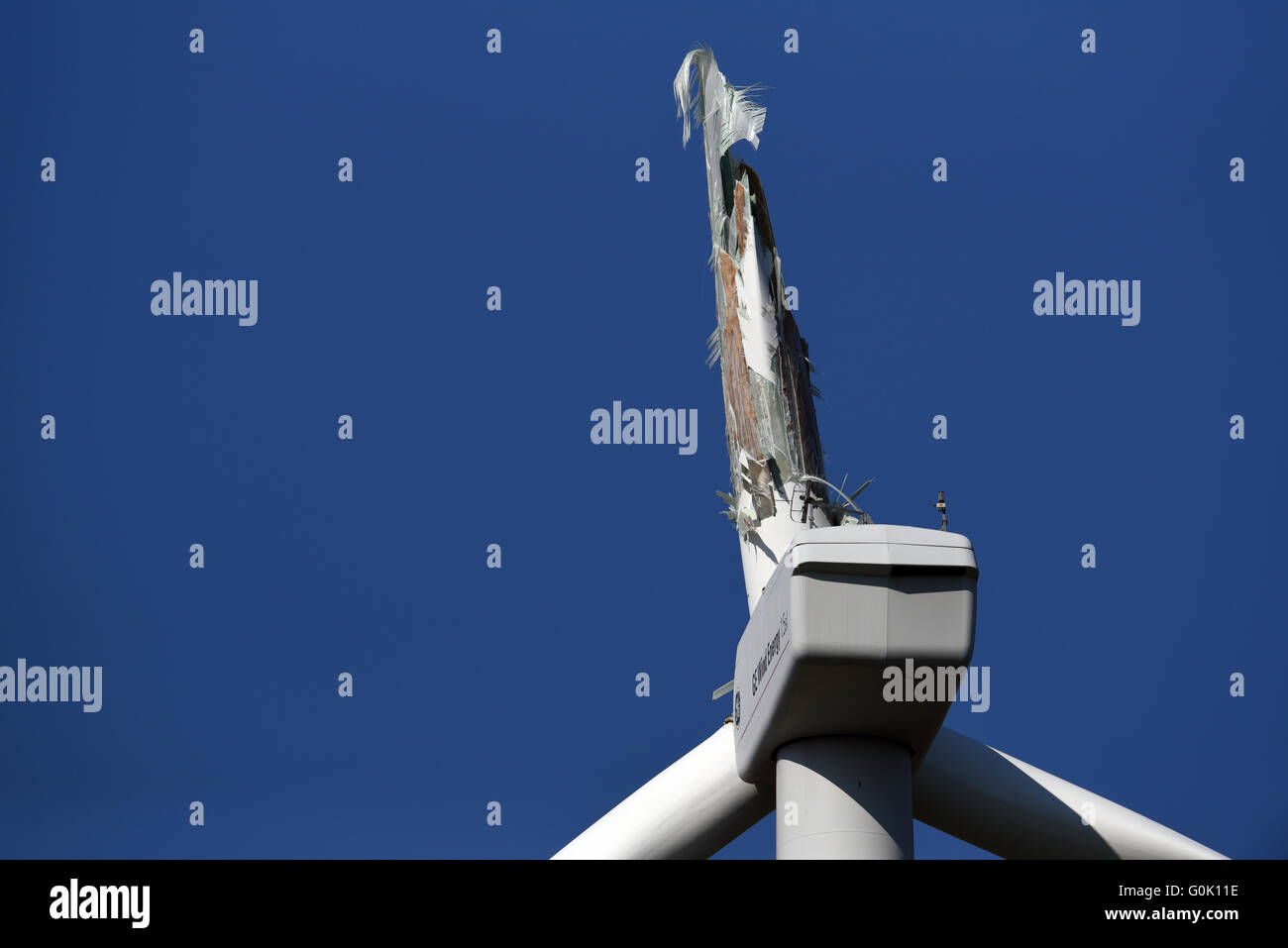 A wind turbine with a broken rotor seen on a field near a wind farm ...