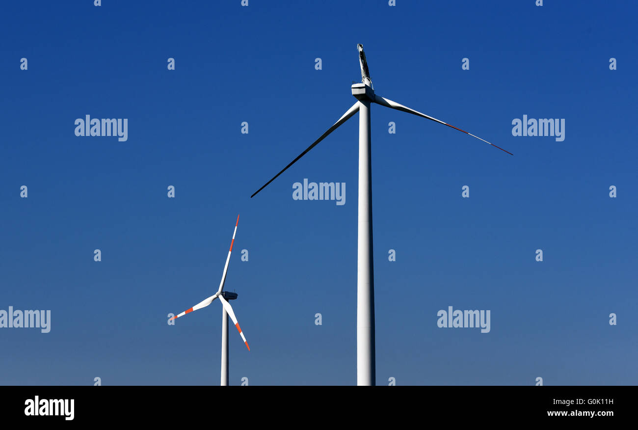 A wind turbine with a broken rotor seen on a field near a wind farm ...