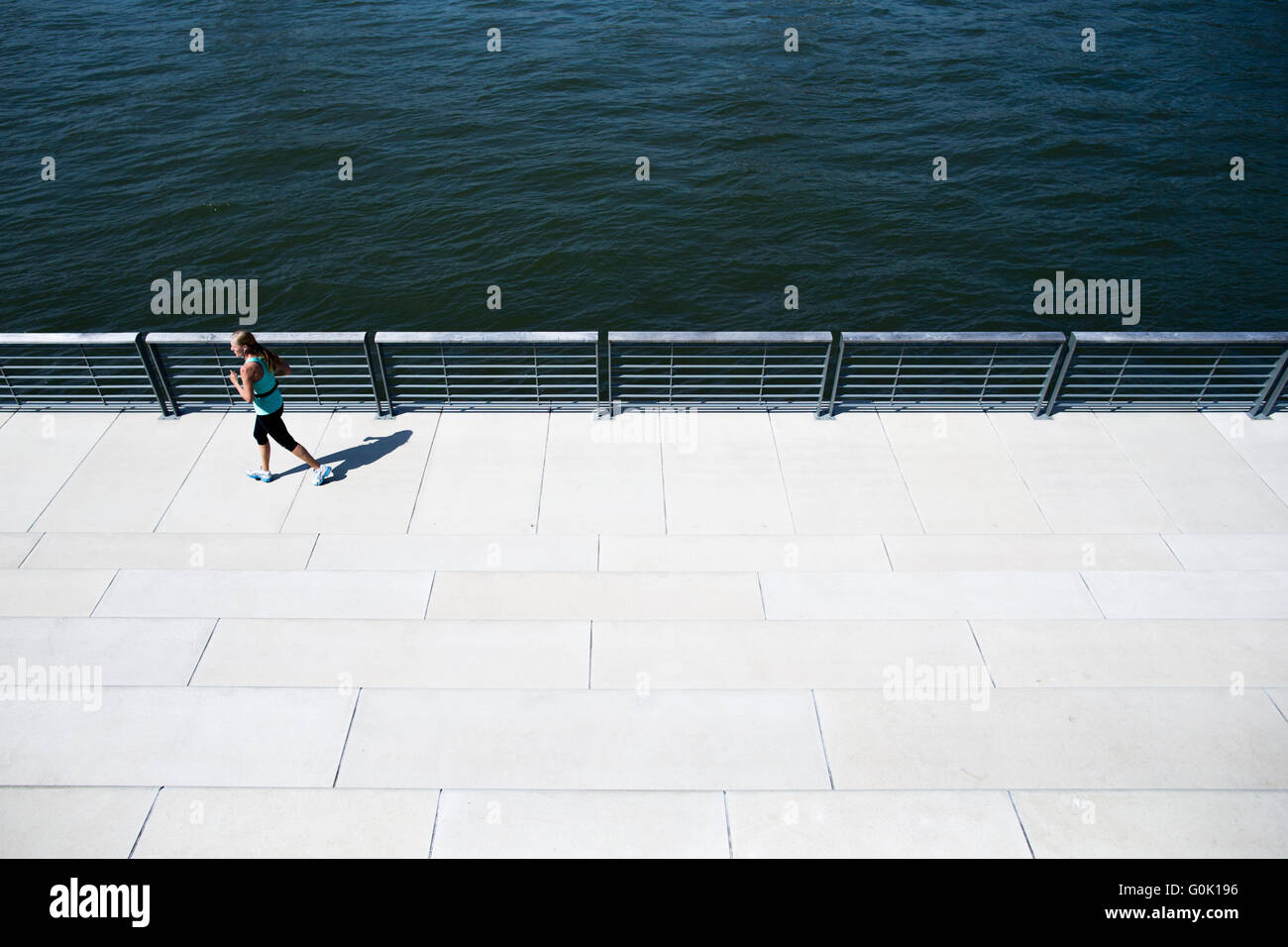 A woman jogs along the Rhine boulevard in sunny weather in Cologne ...