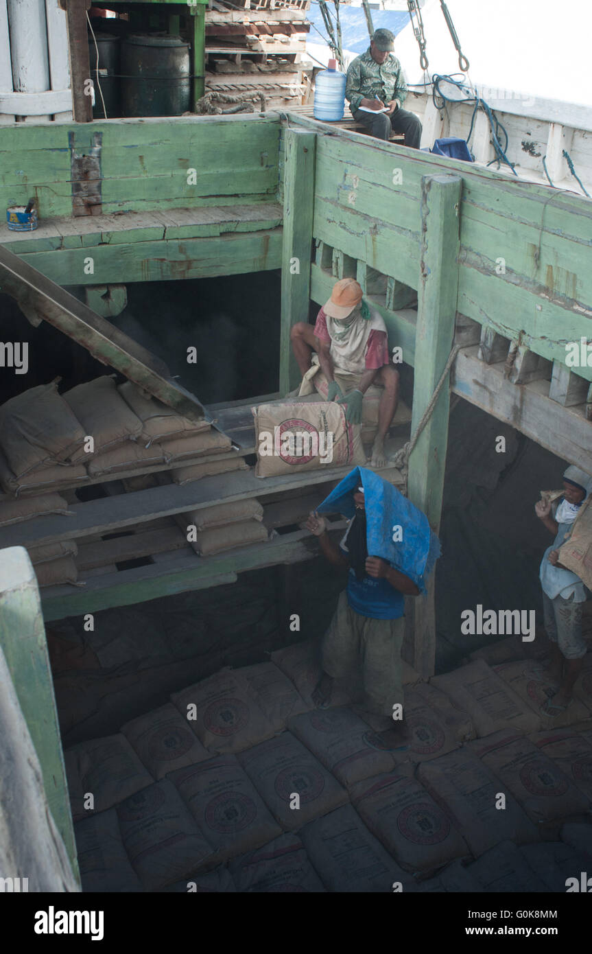 Workers wait inside the hull of a boat loaded with cement at Paotere ...