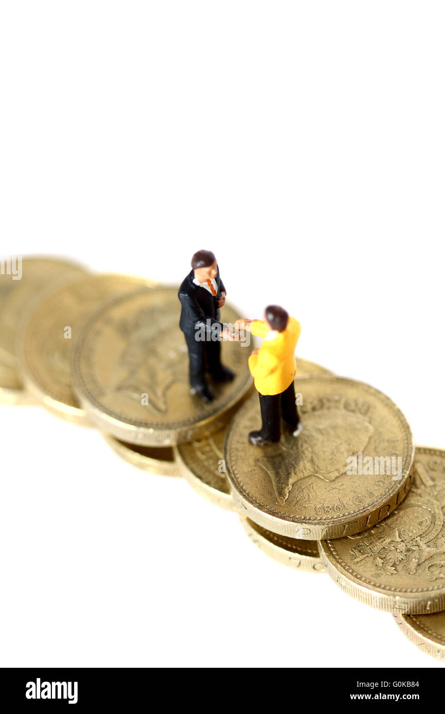 Miniature businessmen shaking hands on pound coins Stock Photo - Alamy