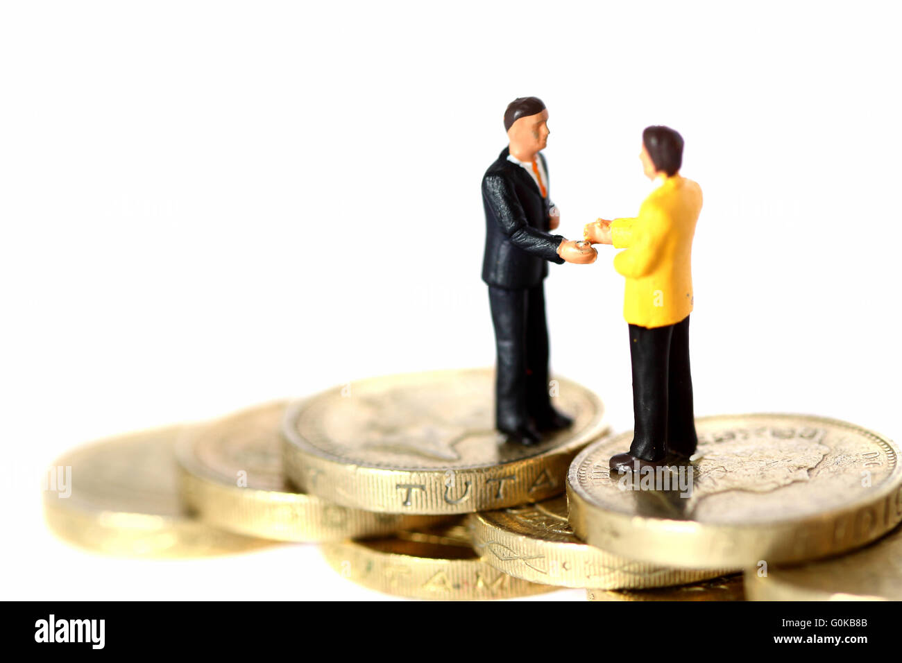 Miniature businessmen shaking hands on pound coins Stock Photo - Alamy