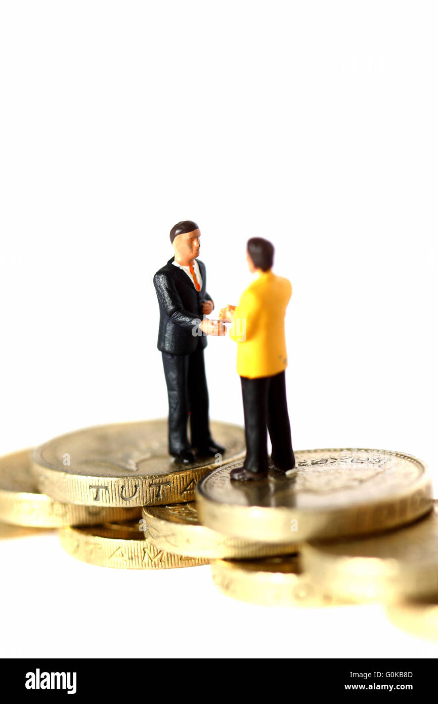 Miniature businessmen shaking hands on pound coins Stock Photo - Alamy