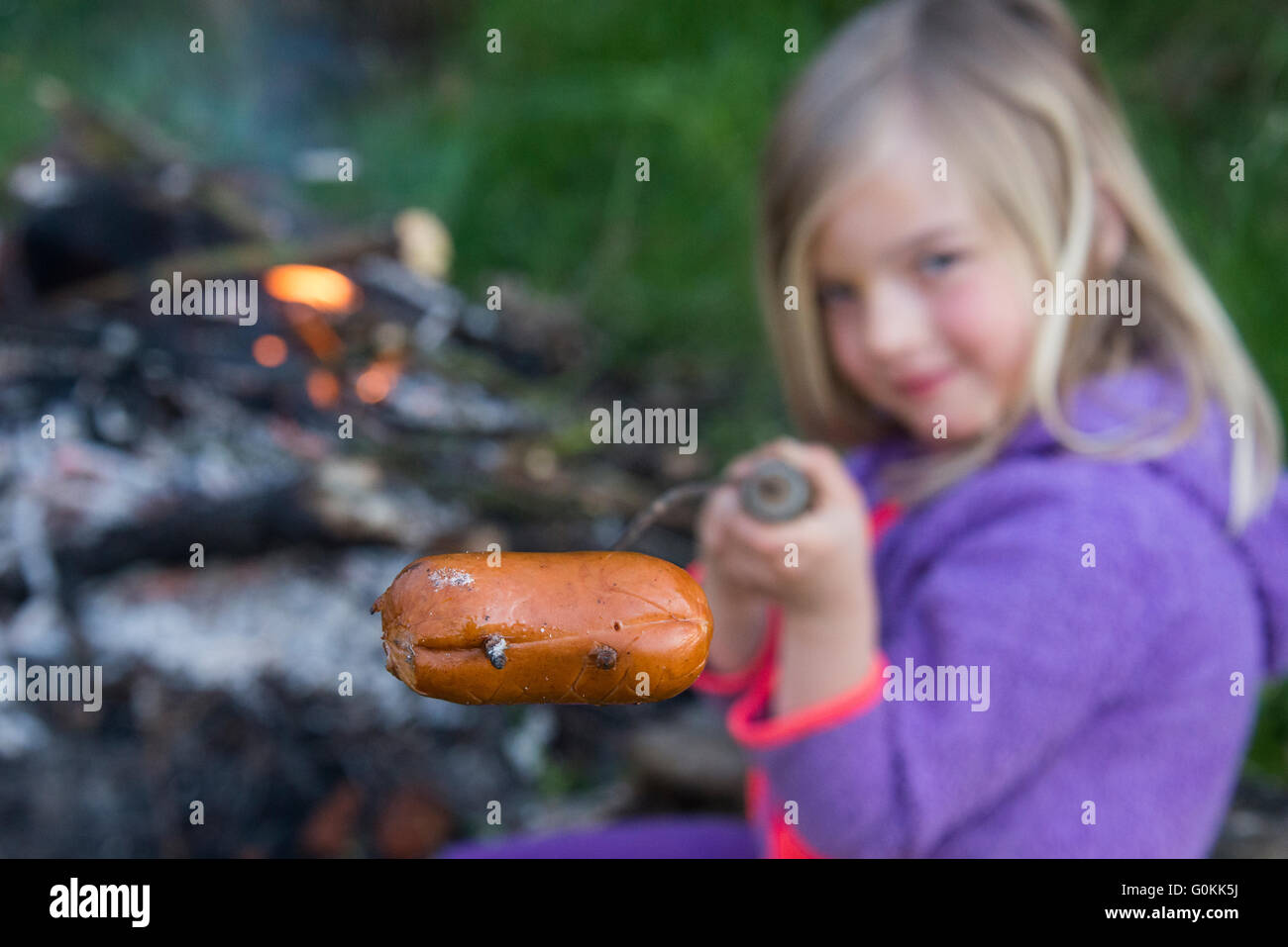 Girl Preparing and Eating Sausage Cooked On Camp Fire Stock Photo - Alamy