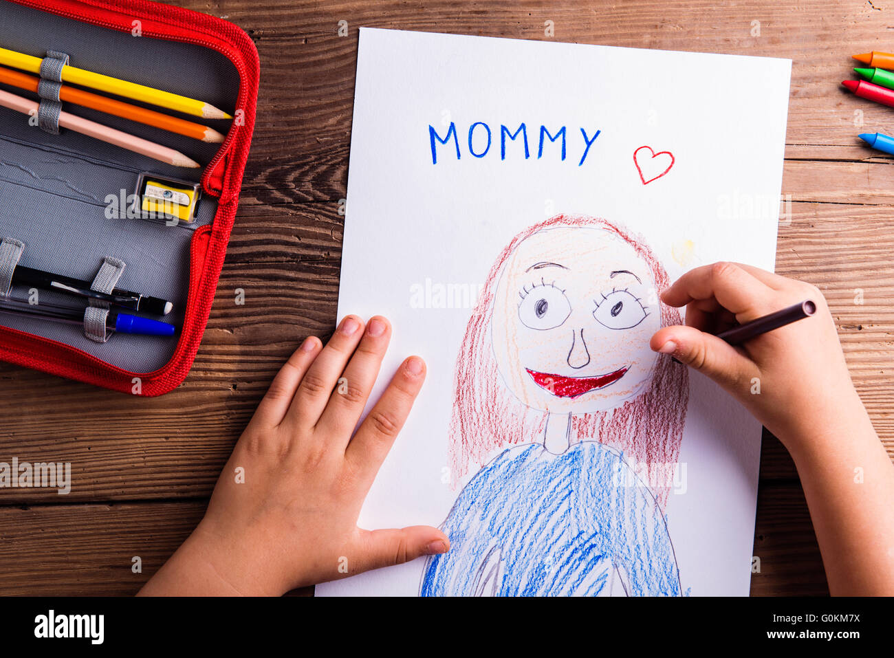Unrecognizable girl drawing picture of her mother. Wooden backgr Stock ...