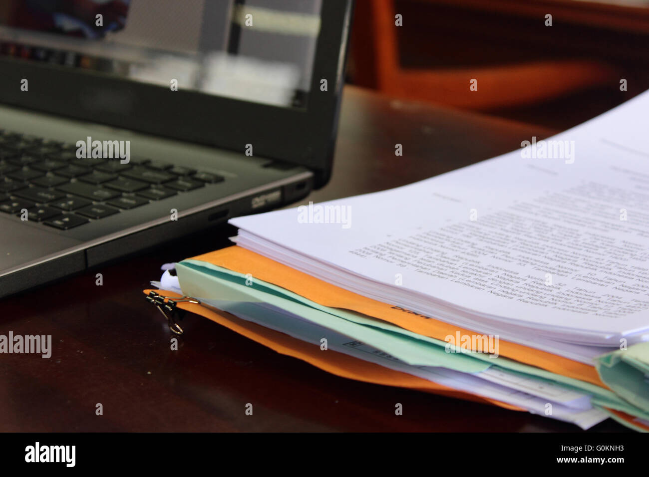Laptop with stack of folders on table Stock Photo - Alamy