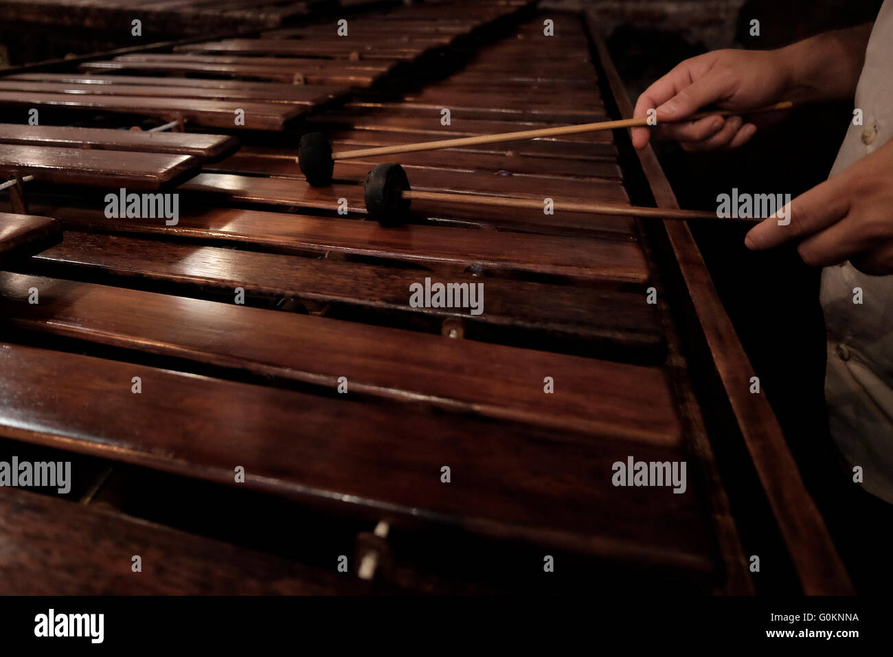 A person holding mallets on the keys of an old wooden marimba in ...