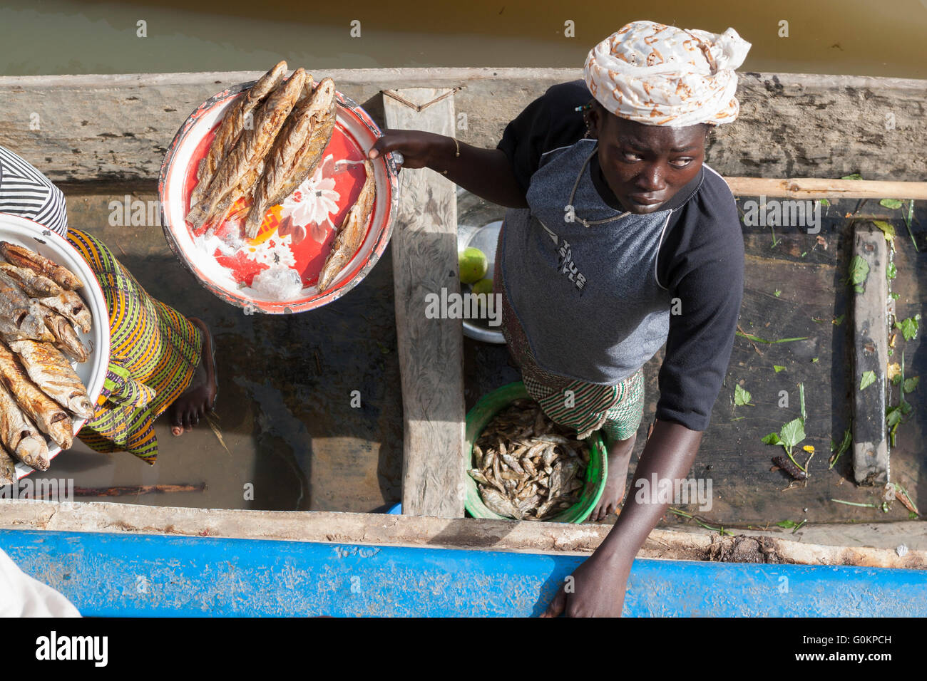 African woman selling grilled fish on a pirogue Stock Photo - Alamy