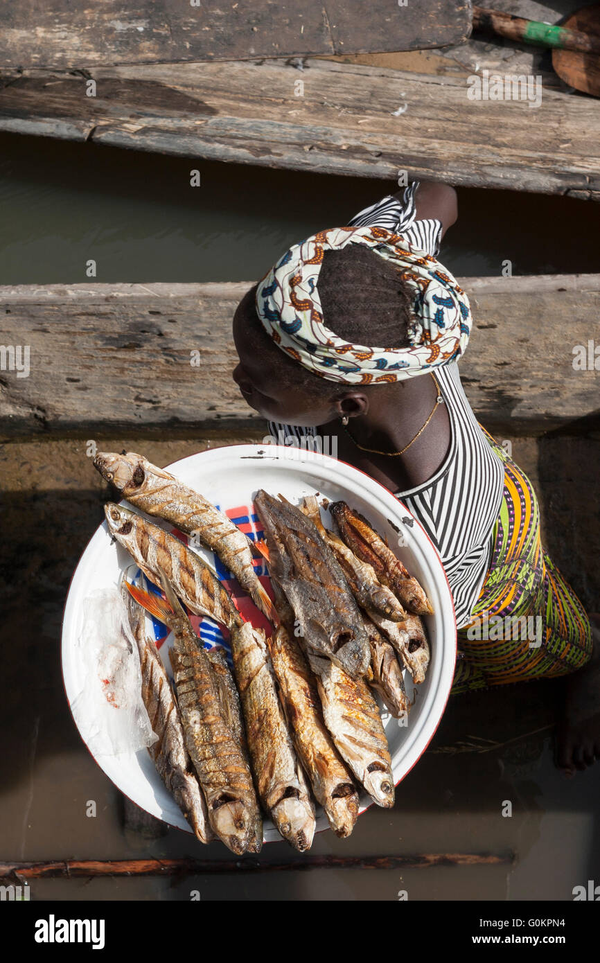African woman selling grilled fish on a pirogue Stock Photo - Alamy