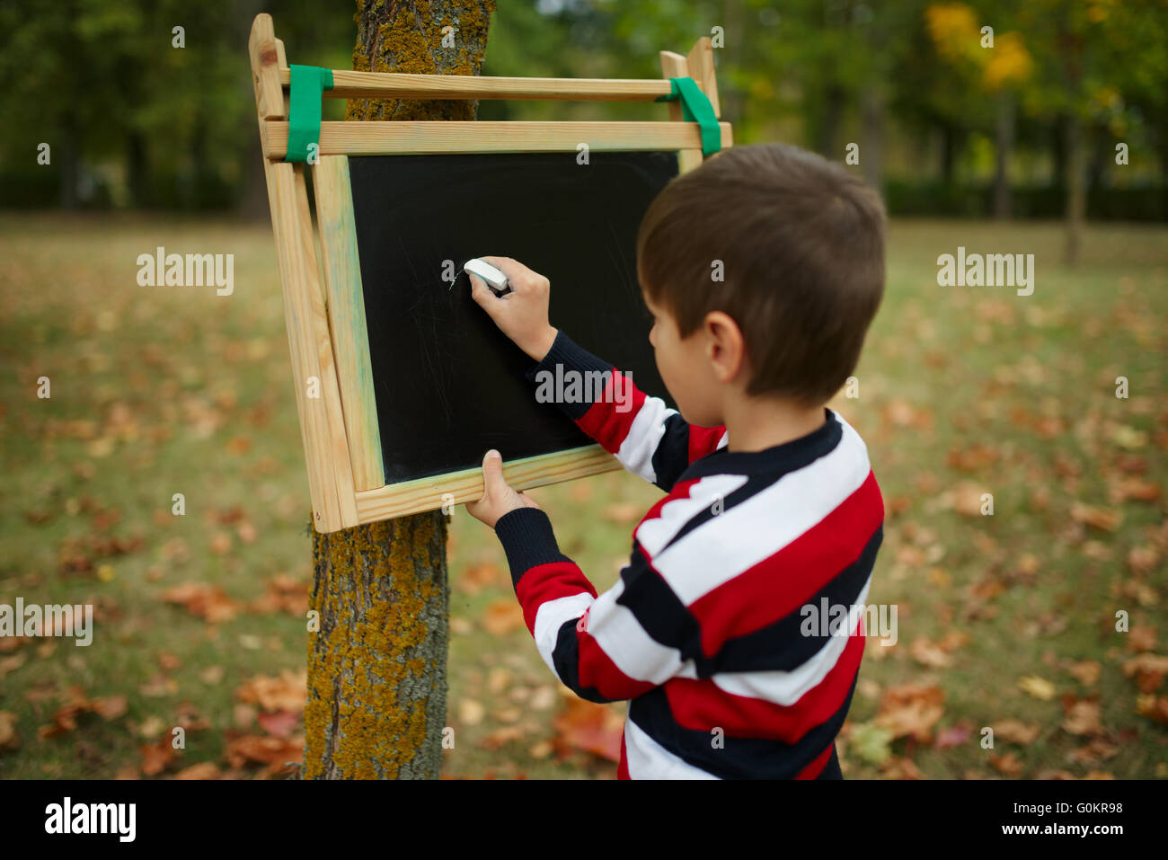little happy boy writing on blackboard Stock Photo - Alamy