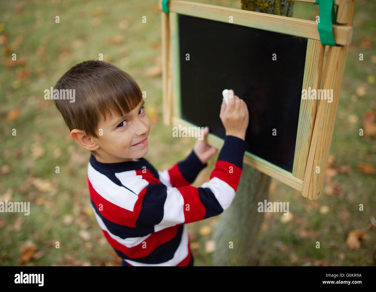 little happy boy writing on blackboard Stock Photo - Alamy