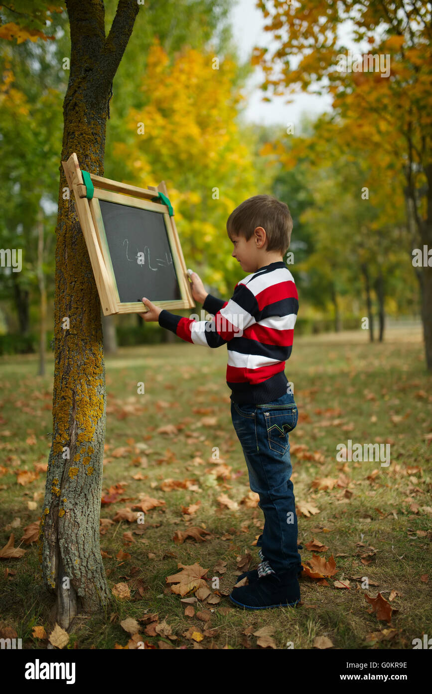 little happy boy writing on blackboard Stock Photo - Alamy