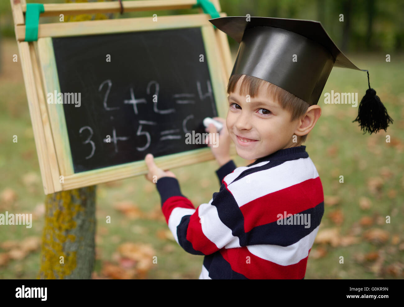 little happy boy writing on blackboard Stock Photo - Alamy