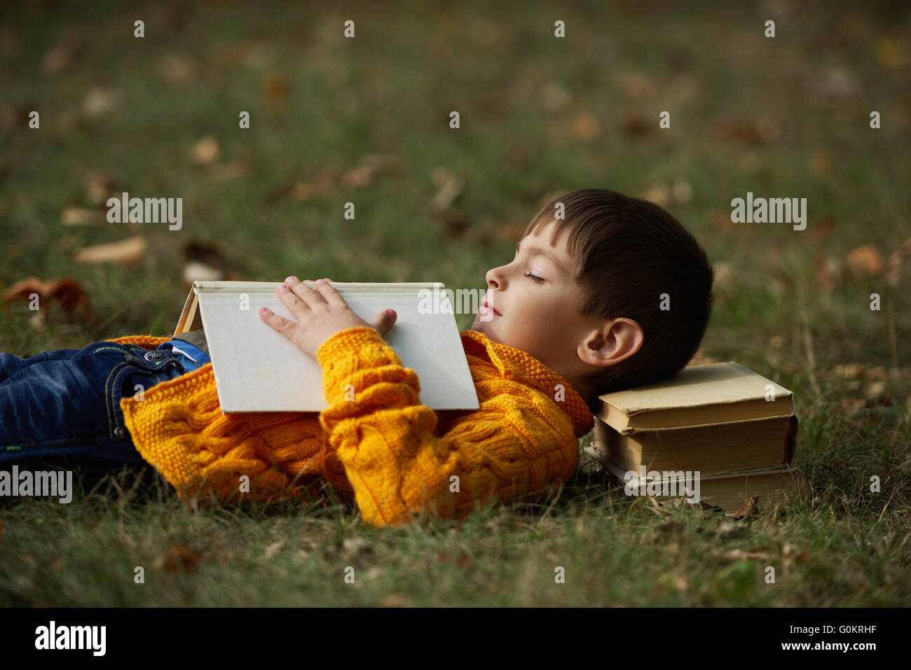 little boy sying on stack of books Stock Photo - Alamy