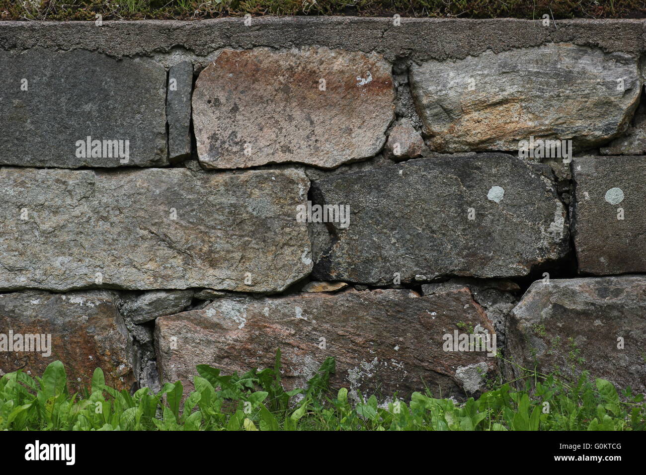 Old fashioned stone wall with grass on the ground Stock Photo - Alamy