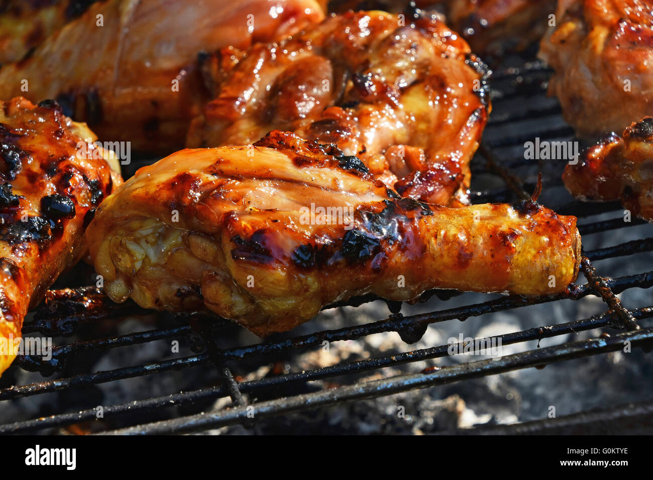Grilled barbecue chicken legs meat portions cooked on fire grill close ...