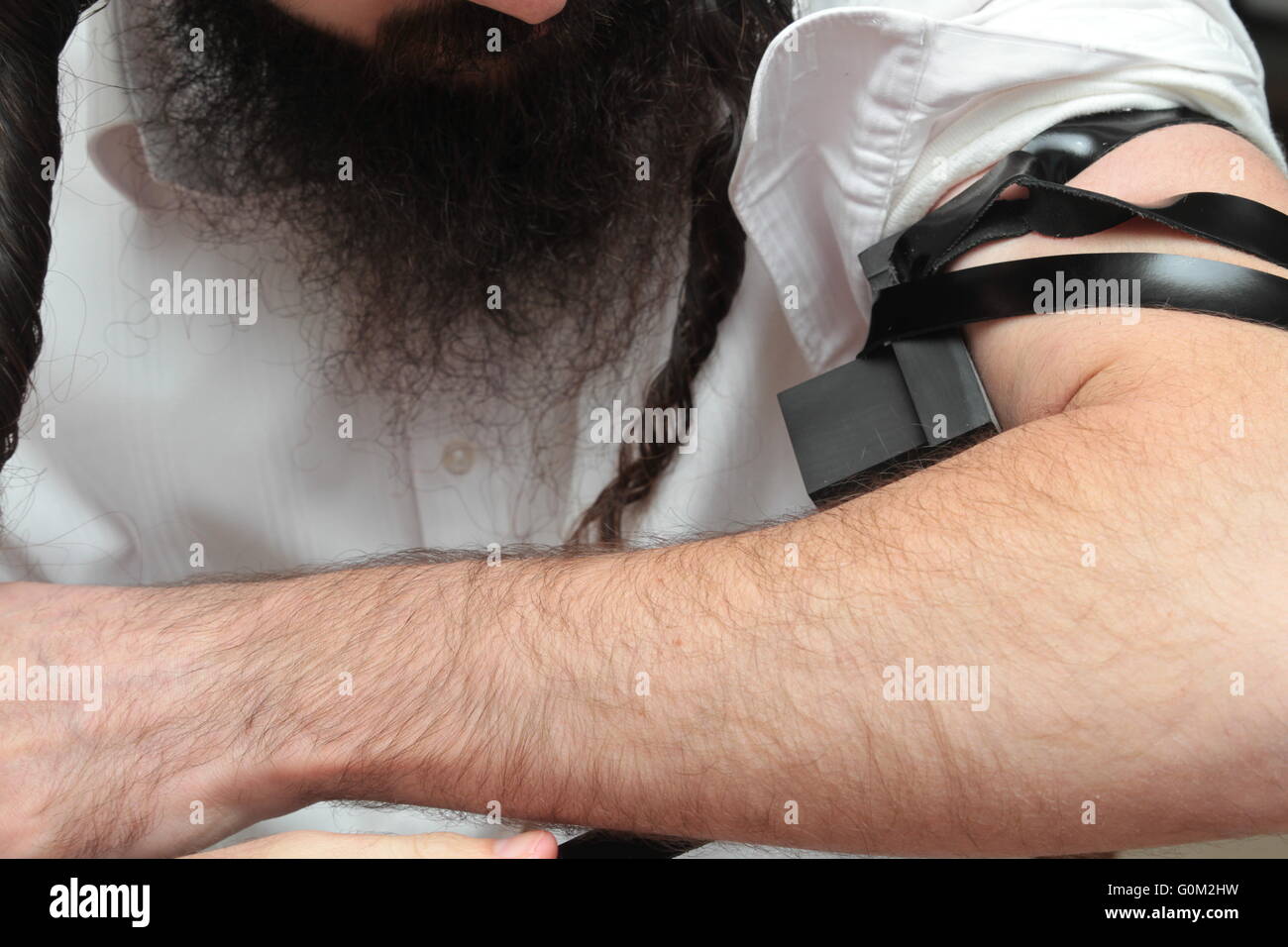 Jewish Man wrapped in tefillin pray . A religious orthodox Jew with arm ...