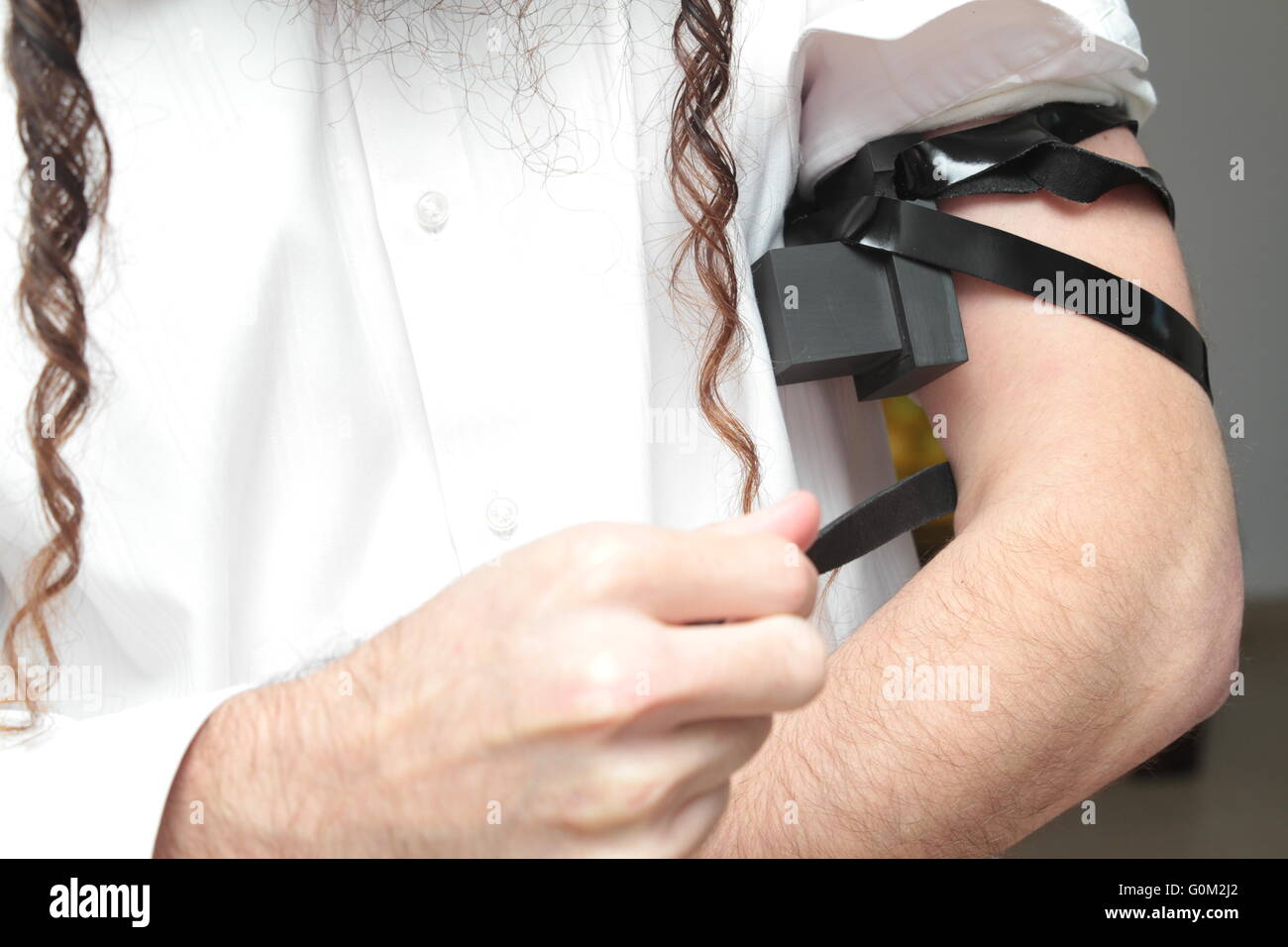 Jewish Man wrapped in tefillin pray . A religious orthodox Jew with arm ...