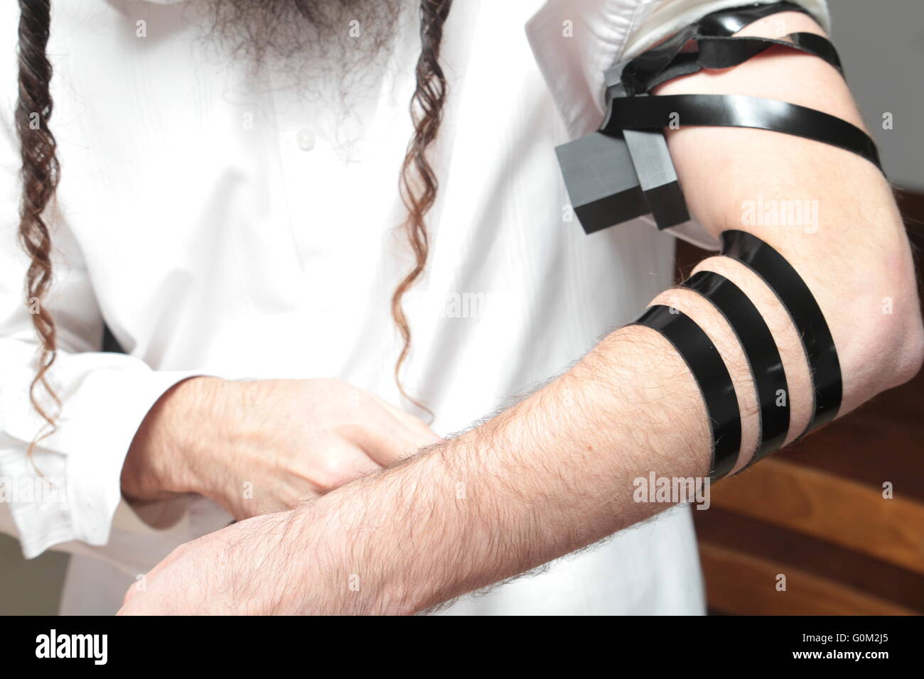 Jewish Man wrapped in tefillin pray . A religious orthodox Jew with arm ...