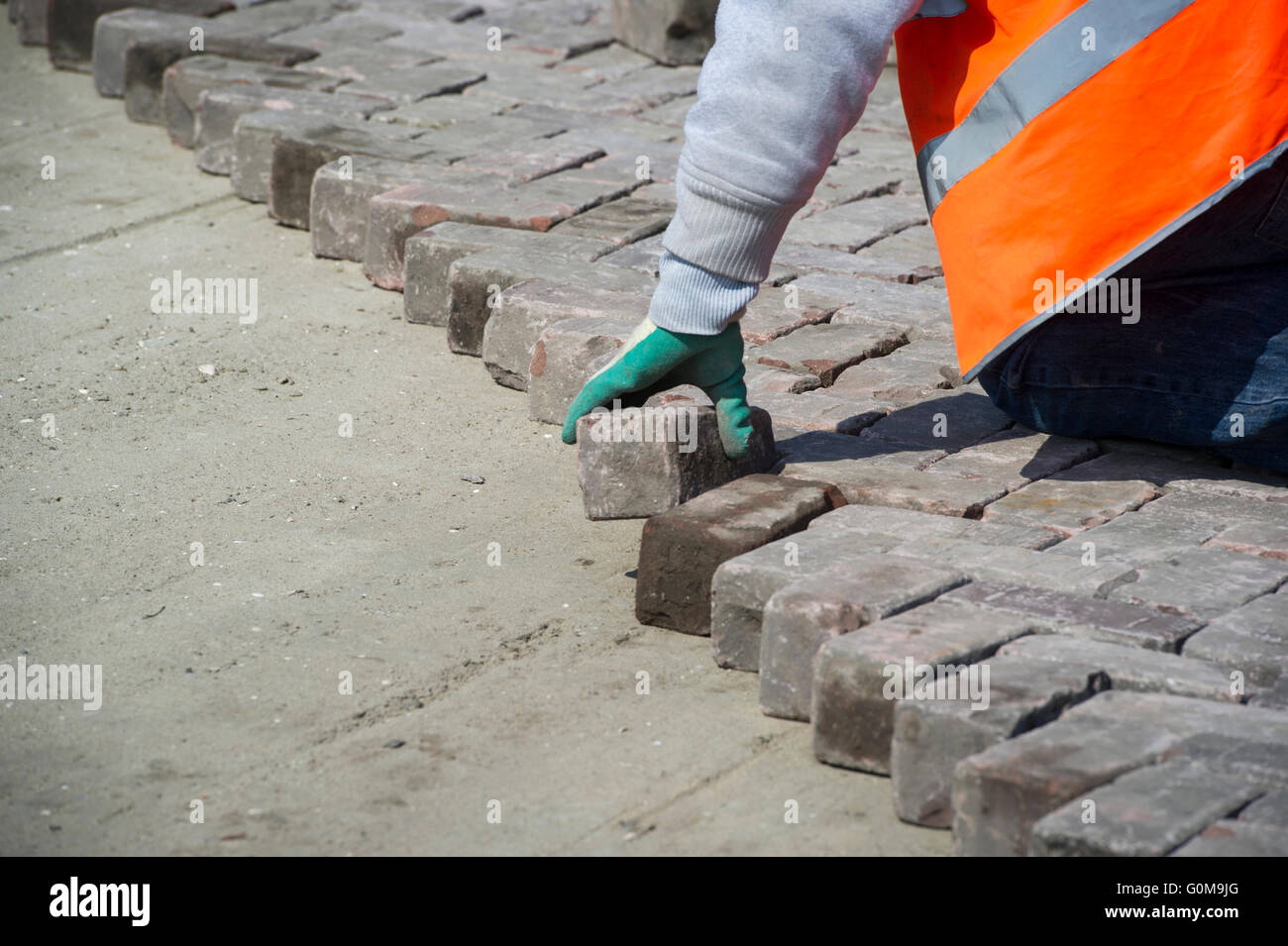 A man laying bricks, paving a street Stock Photo - Alamy