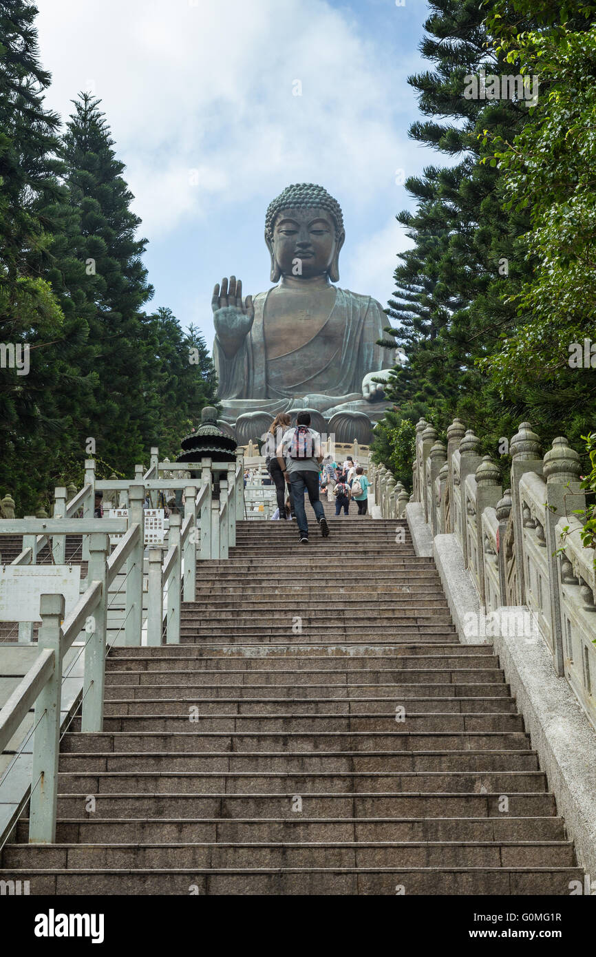 Handful of people climbing long flight of stairs to the Tian Tan Buddha ...