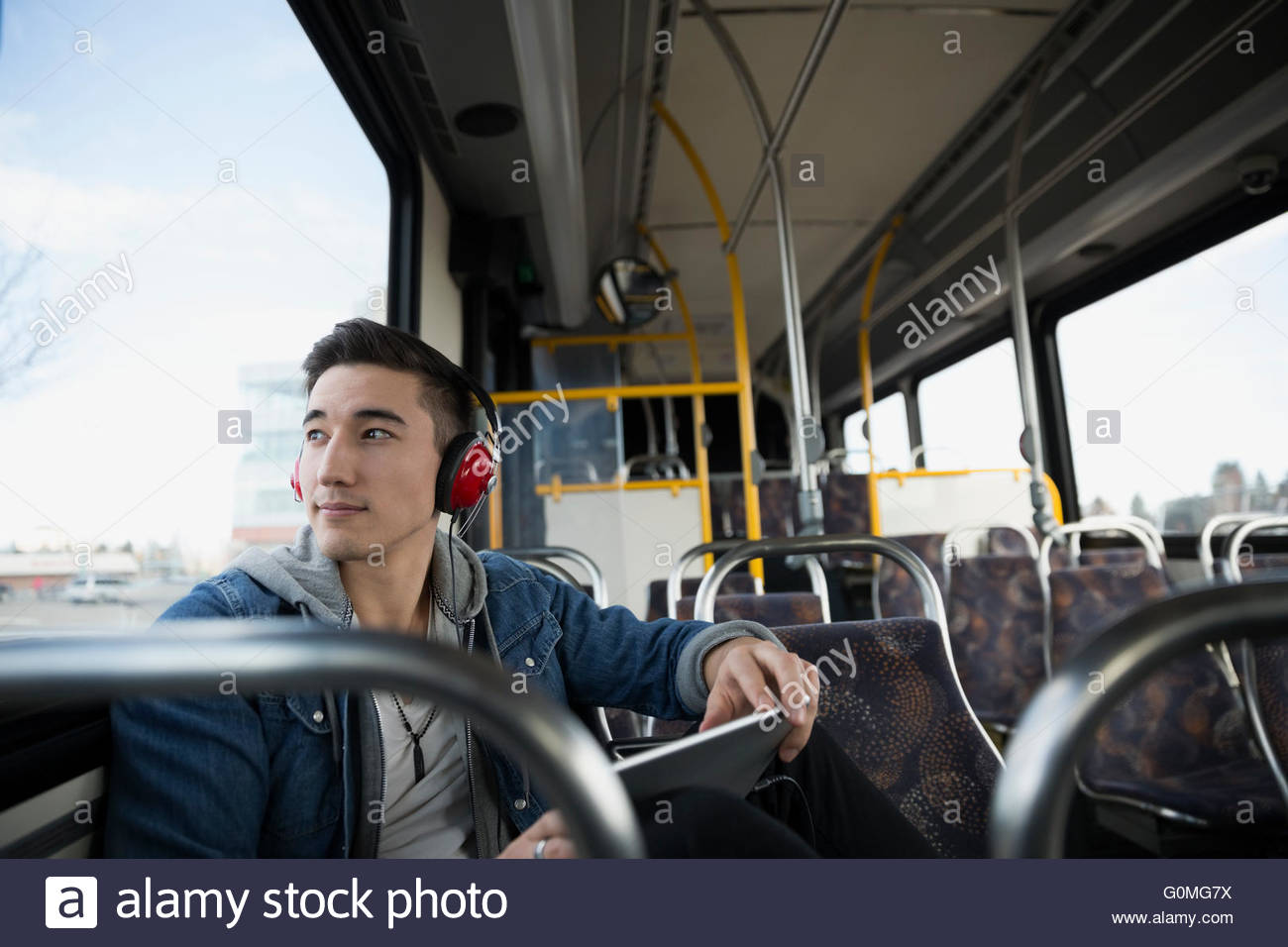 Pensive young man riding bus listening music headphones Stock Photo - Alamy