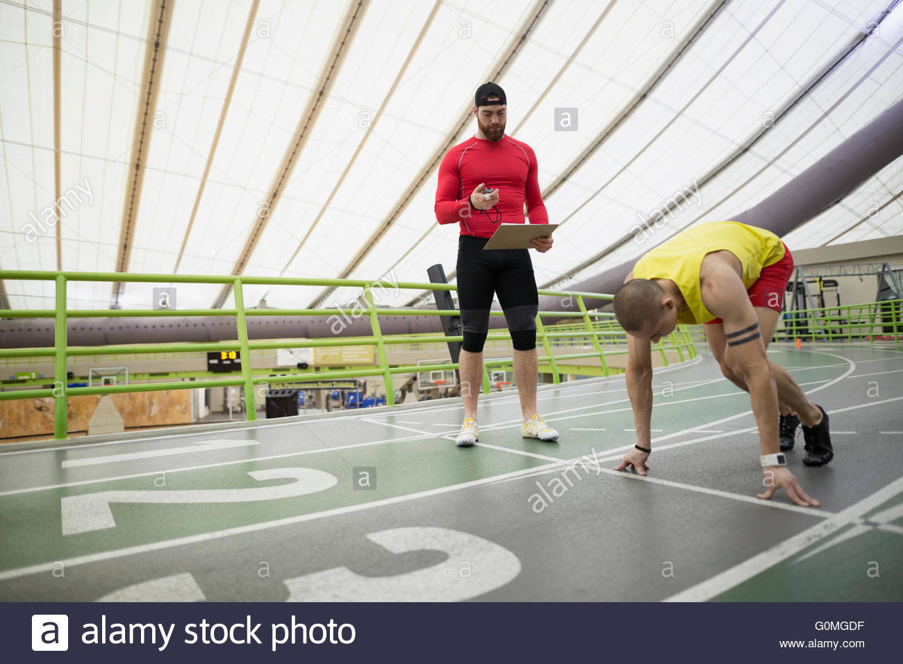 Trainer stopwatch timing runner starting block indoor track Stock Photo ...