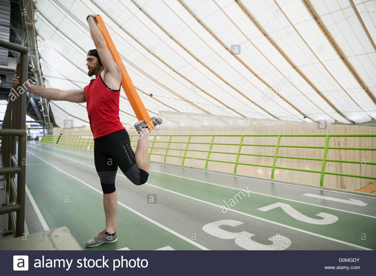 Runner stretching leg with resistance band indoor track Stock Photo - Alamy