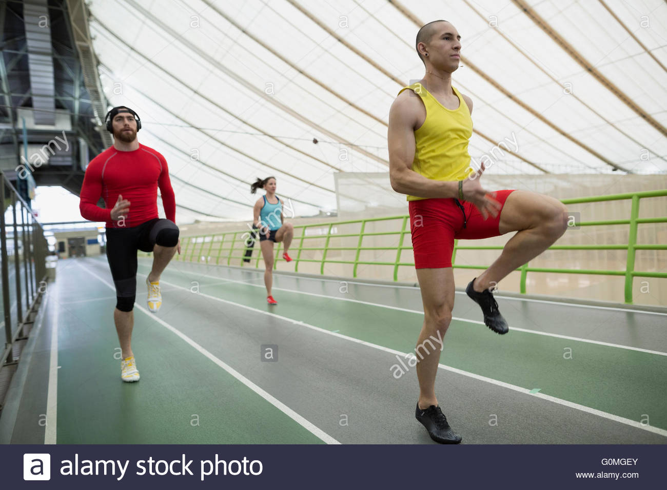 Runners stretching legs on indoor track Stock Photo - Alamy