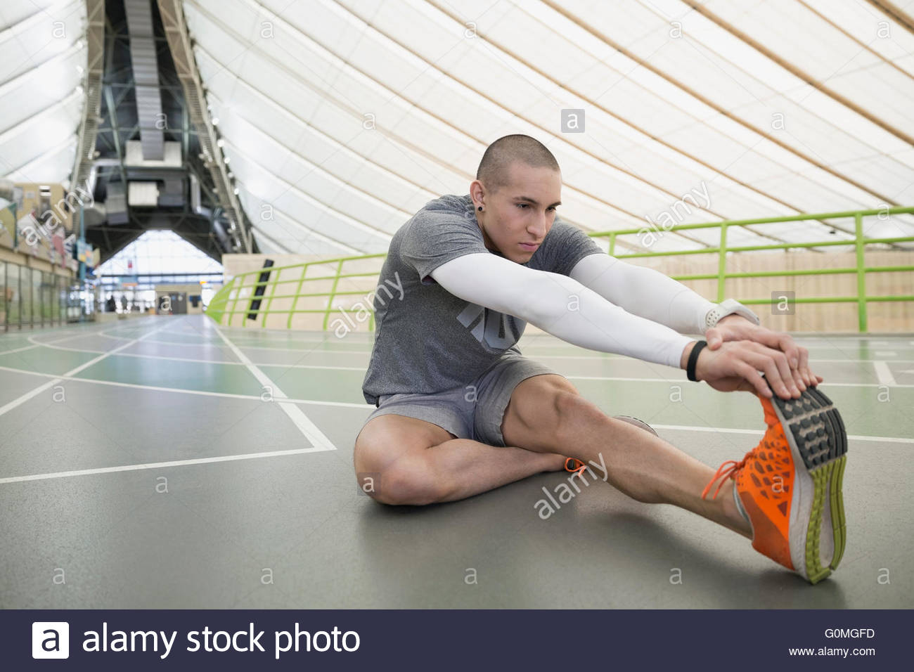 Runner stretching leg at indoor track Stock Photo - Alamy
