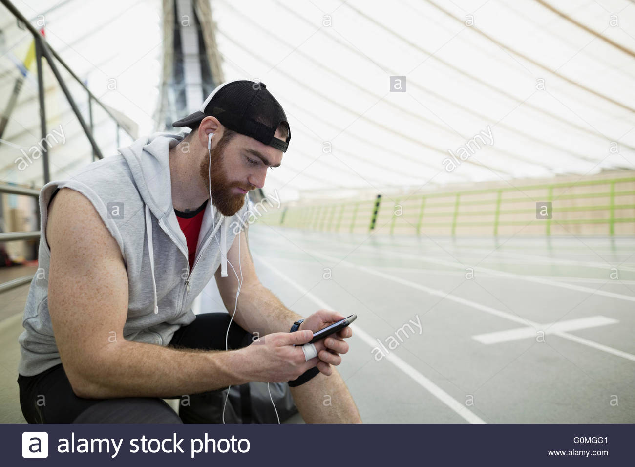 Runner with headphones checking cell phone indoor track Stock Photo - Alamy