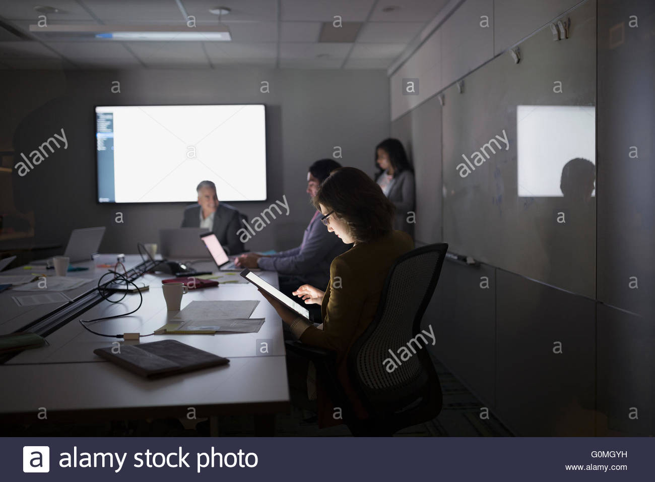 Businesswoman using digital tablet dark conference room meeting Stock ...