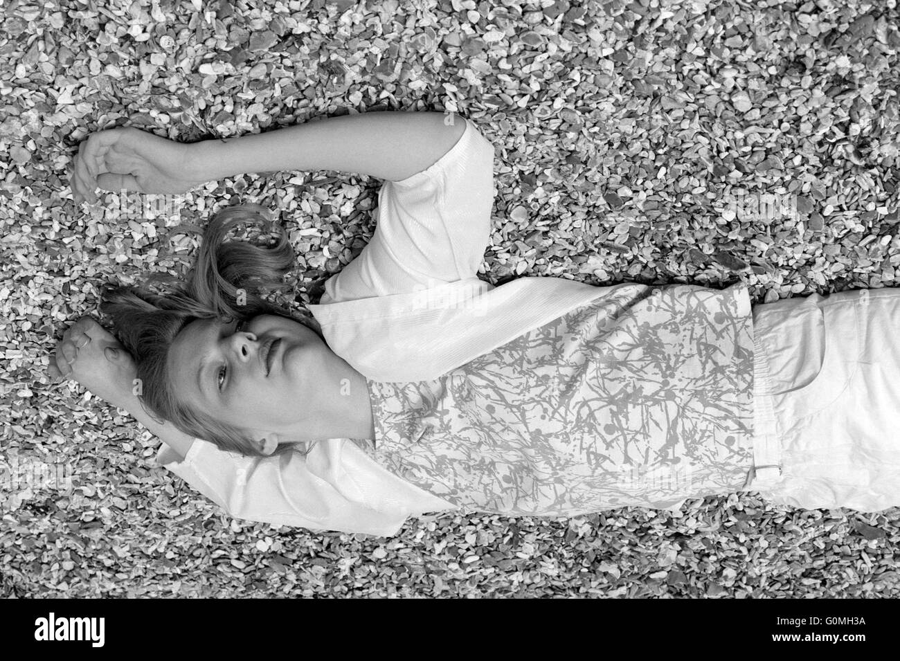 young pretty blonde female laying on pebble beach in southsea england ...