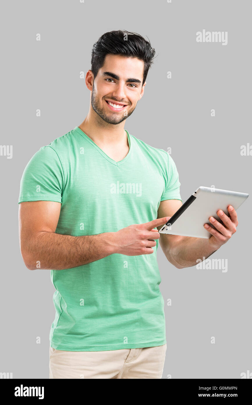 Handsome young man working with a tablet, isolated over gray background ...