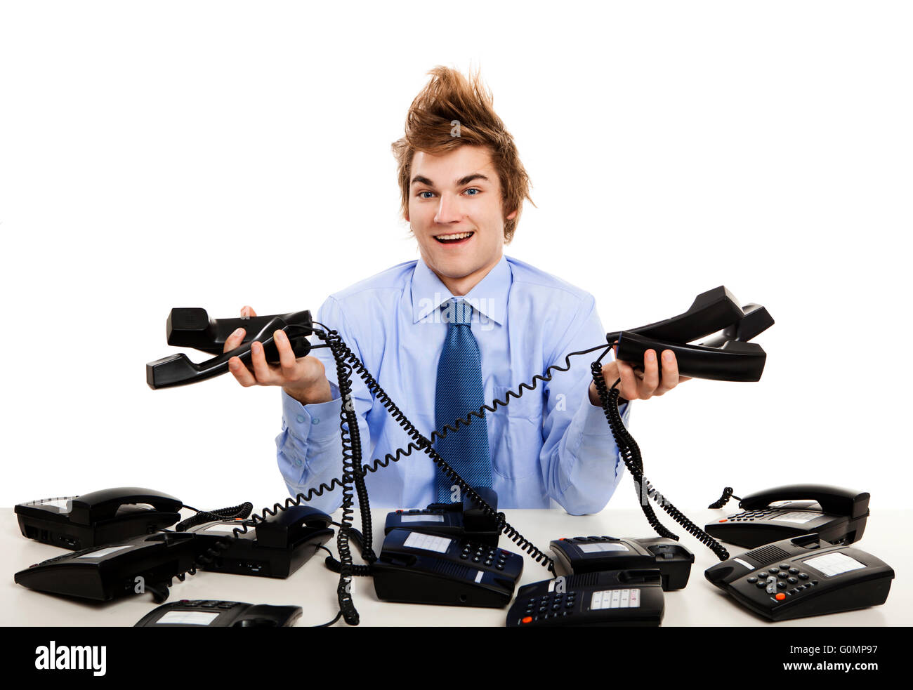 Young man sitting in the office and answering several phones at the ...