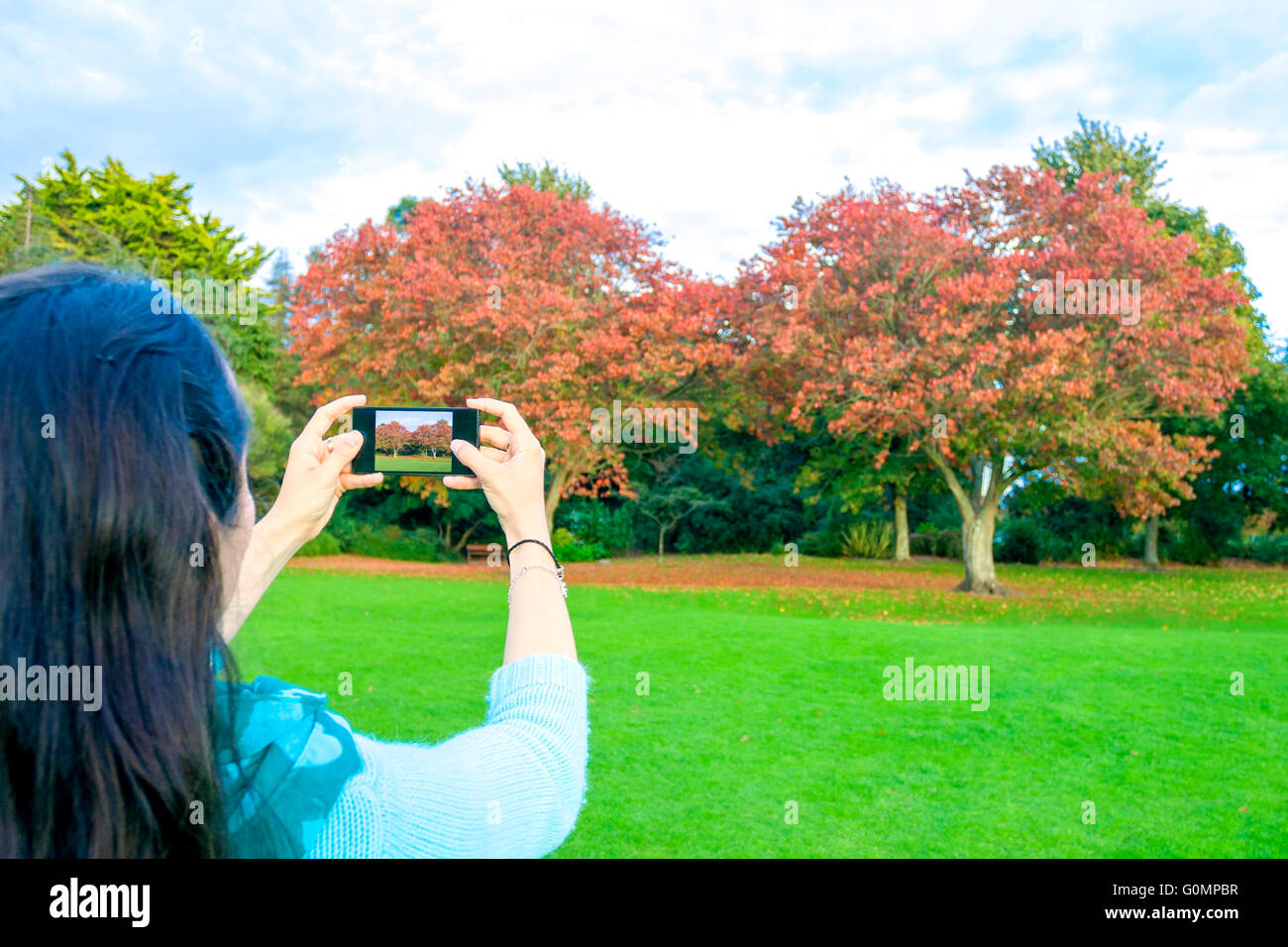 Young adult woman taking a picture in a autumn landscape Stock Photo ...