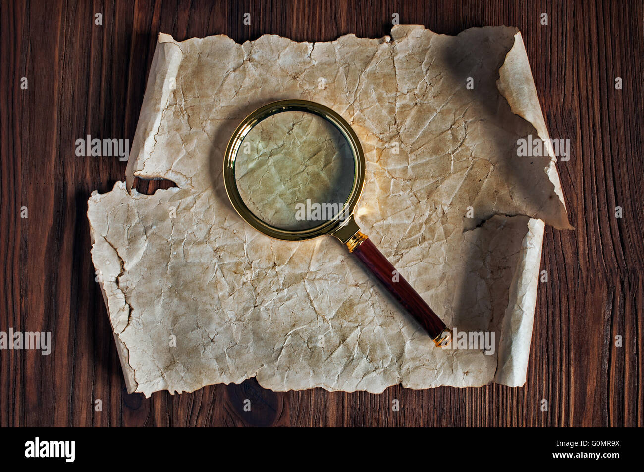 Magnifying glass and old parchment on a wooden table Stock Photo - Alamy